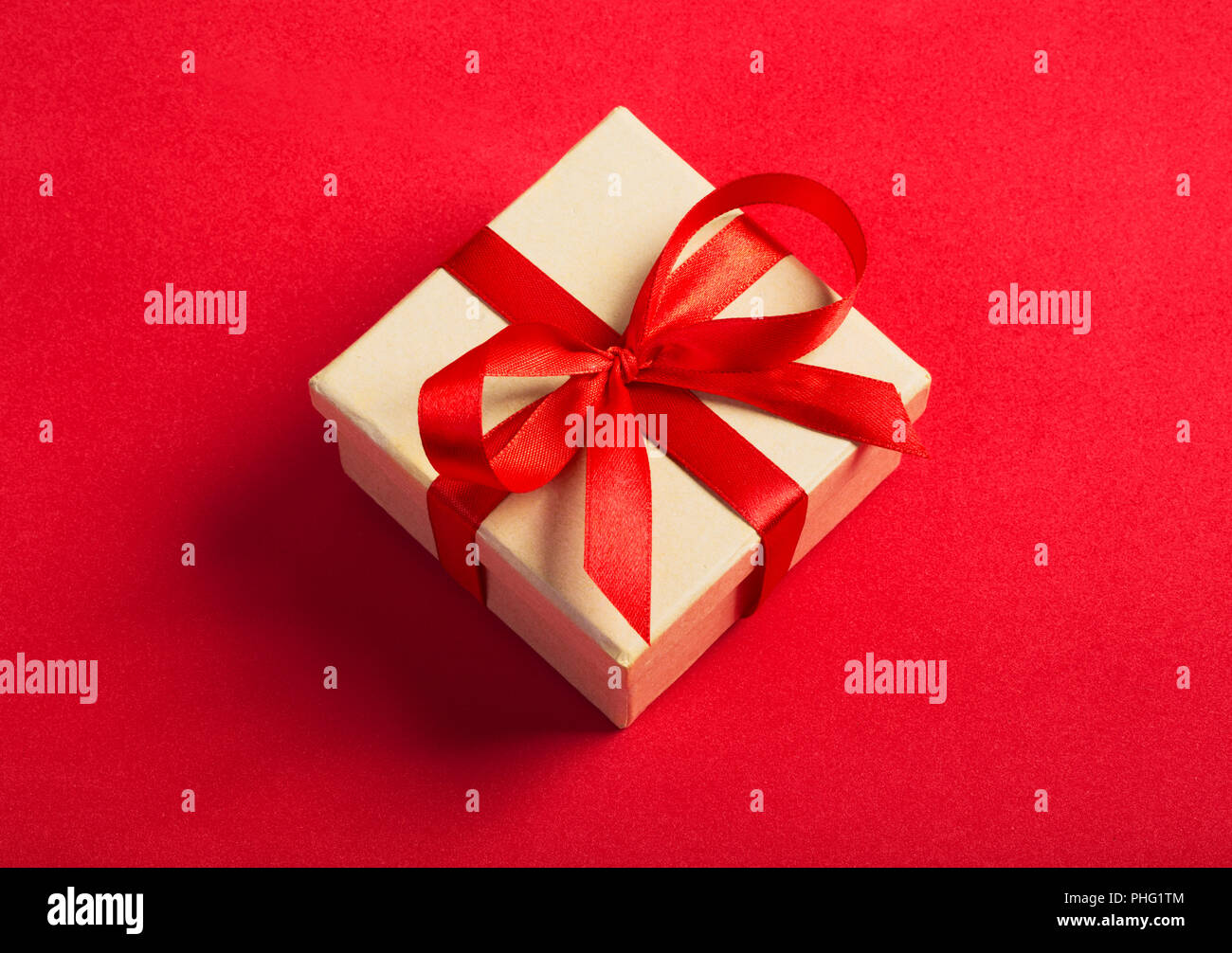 Gift kraft square box with a red ribbon on a red background Stock Photo ...