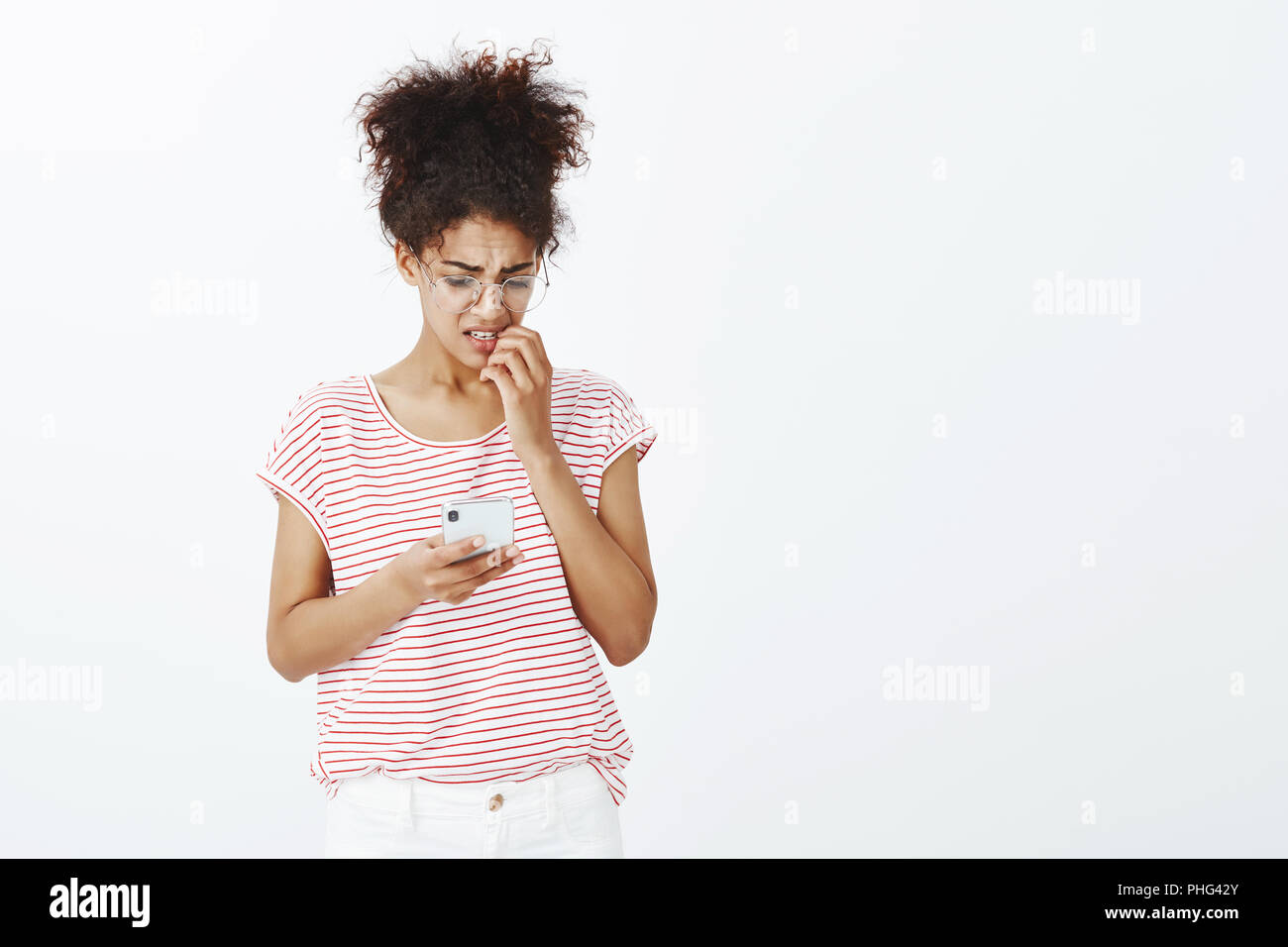 Indoor shot of nervous insecure dark-skinned woman in striped t-shirt ...