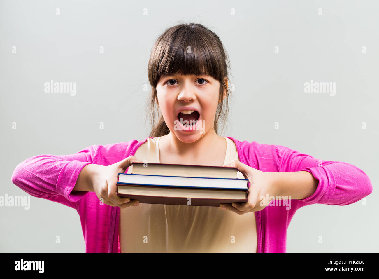 Angry little girl with books Stock Photo - Alamy