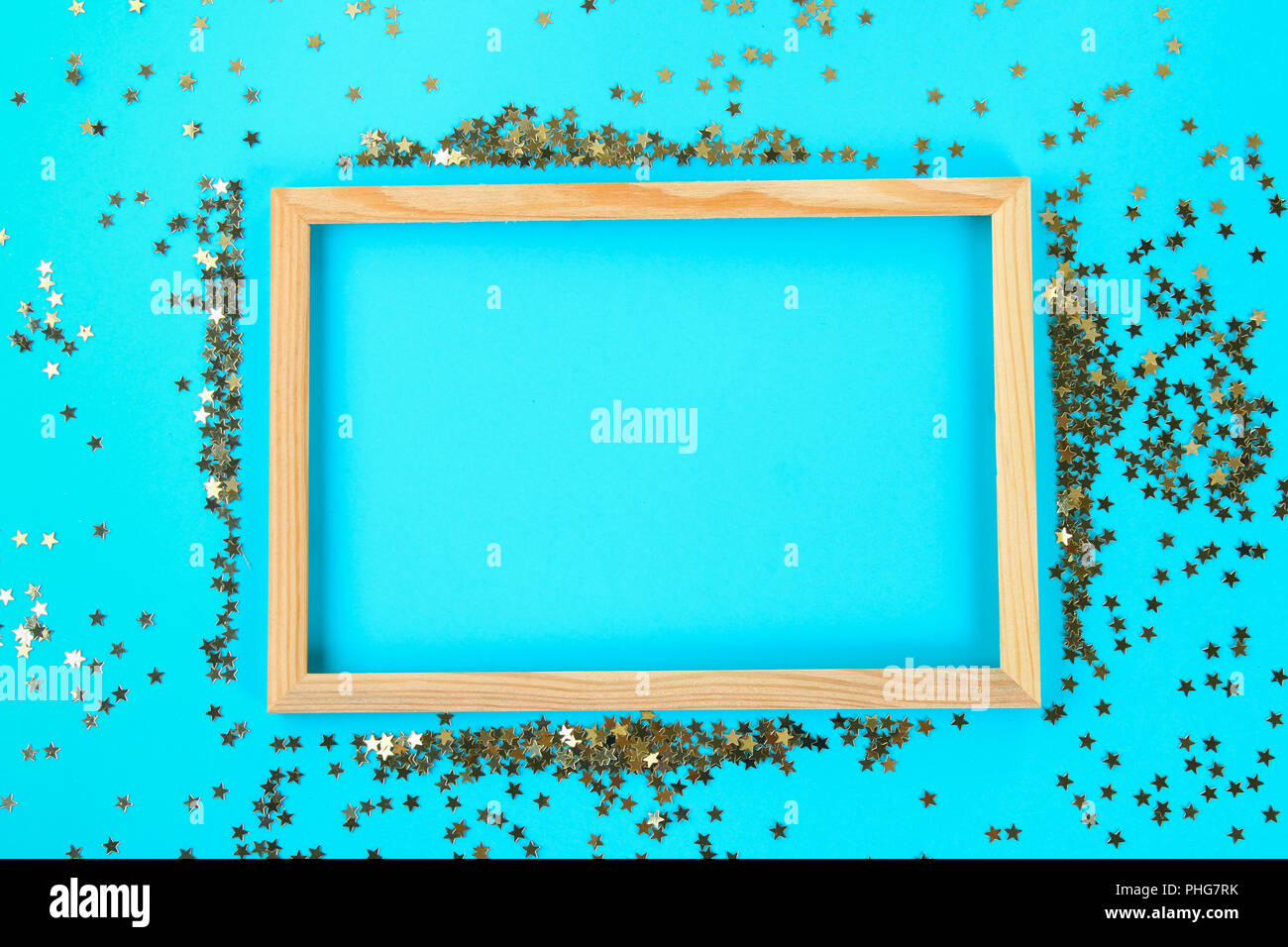 A wooden empty frame on a pastel background surrounded by shiny ...
