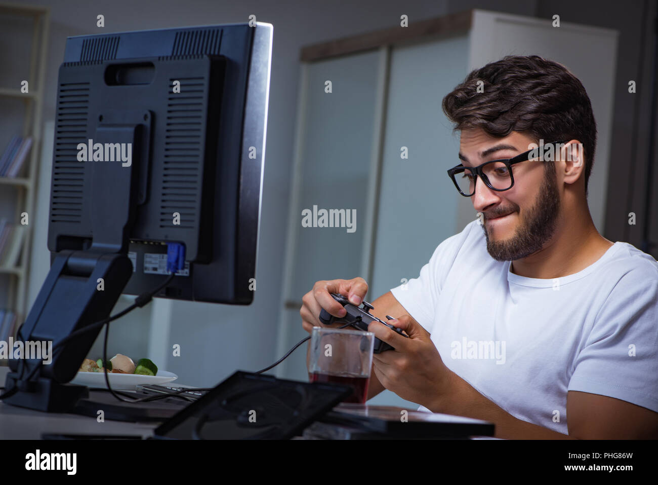 Young man playing games long hours late in the office Stock Photo - Alamy