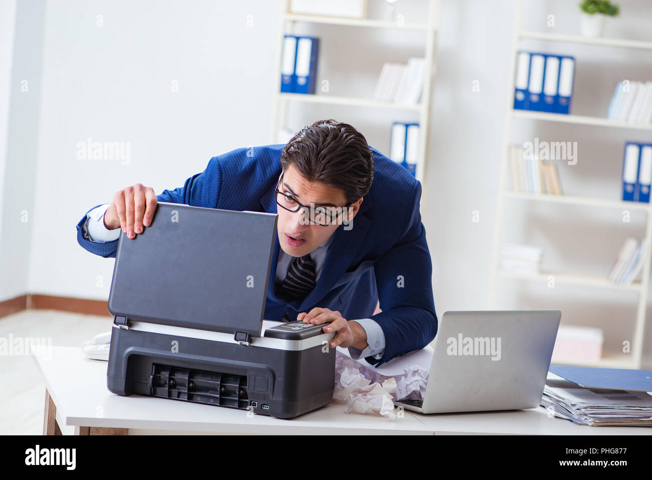 Businessman angry at copying machine jamming papers Stock Photo - Alamy
