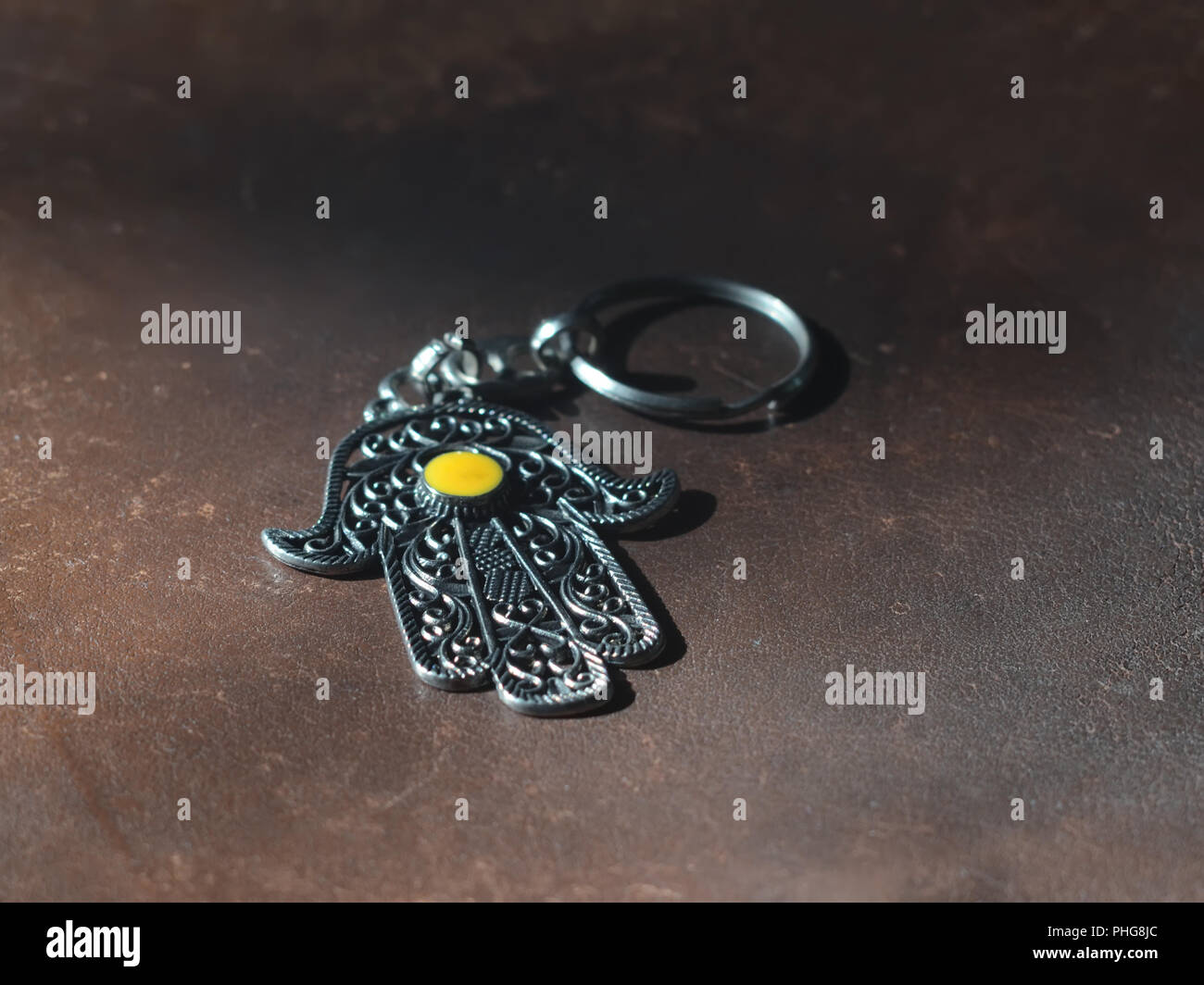A key ring in the form of Fatima Hand on a brown leather background ...