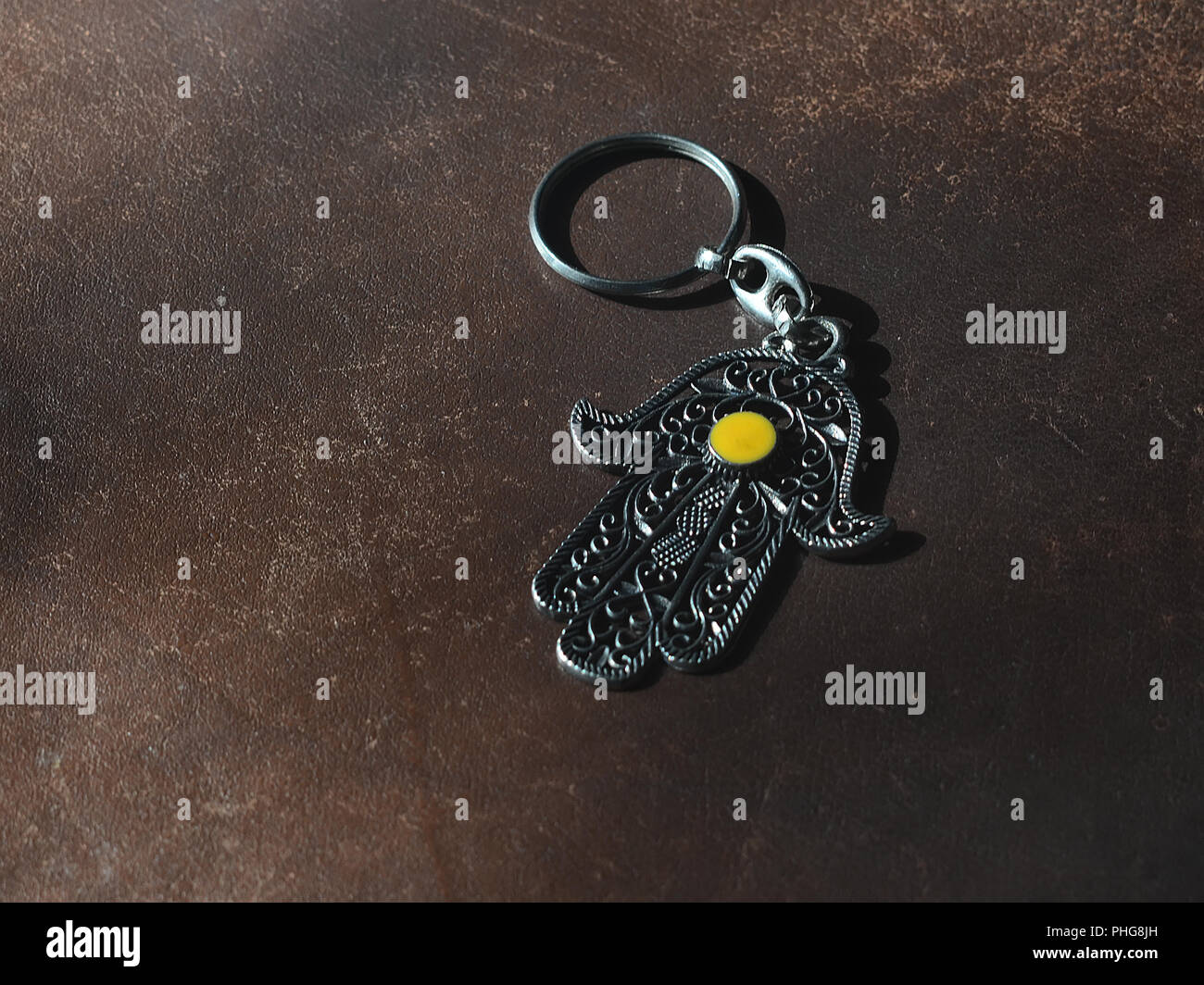 A key ring in the form of Fatima Hand on a brown leather background ...
