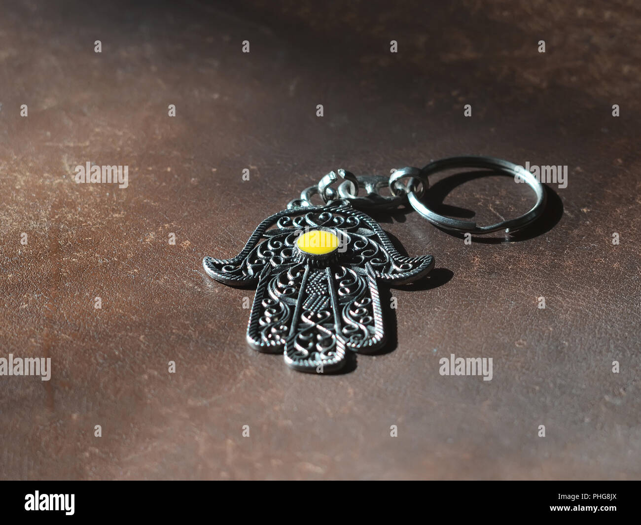A key ring in the form of Fatima Hand on a brown leather background ...