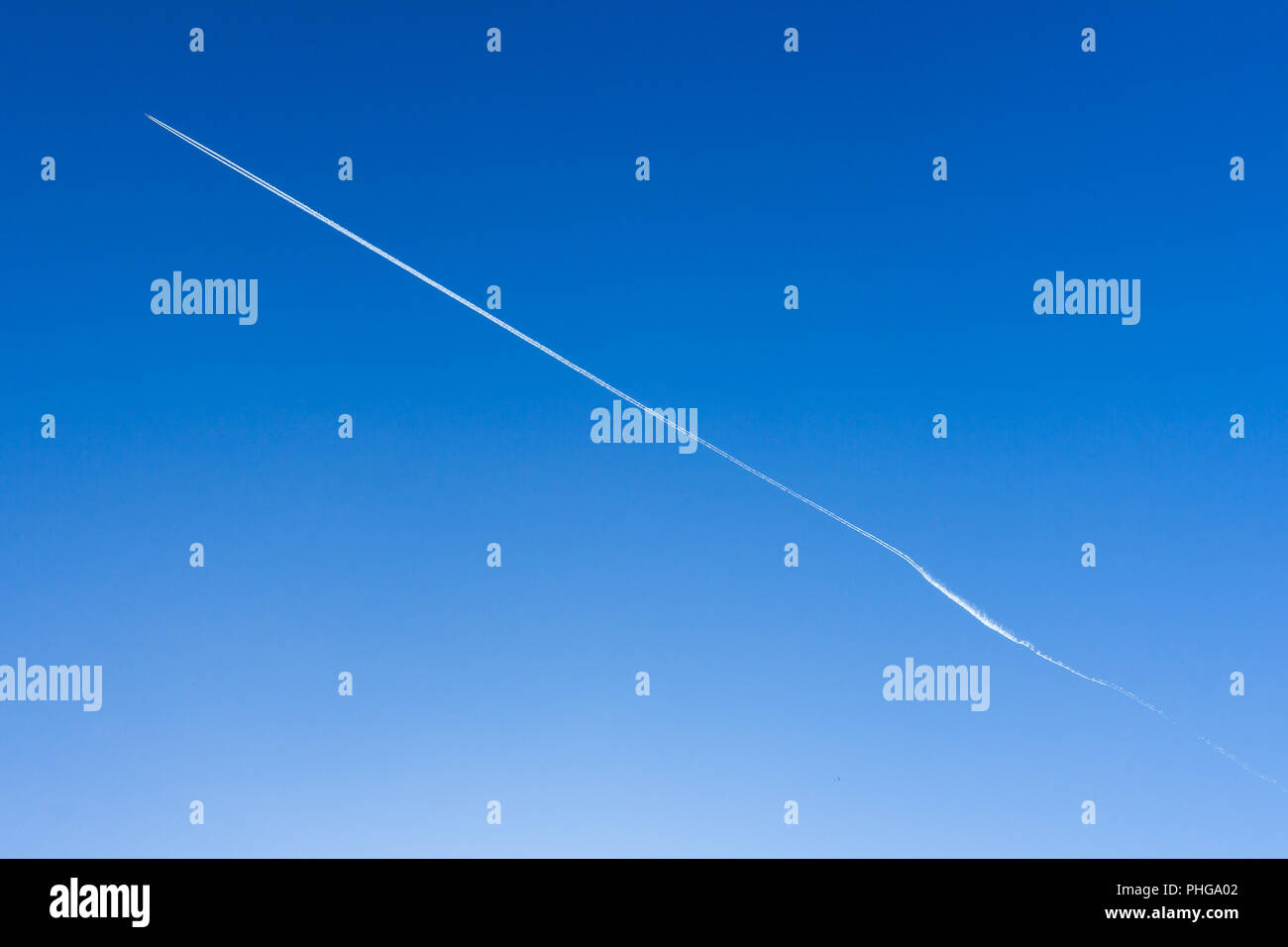 Airplane in the blue sky leaves white stripes behind him Stock Photo ...