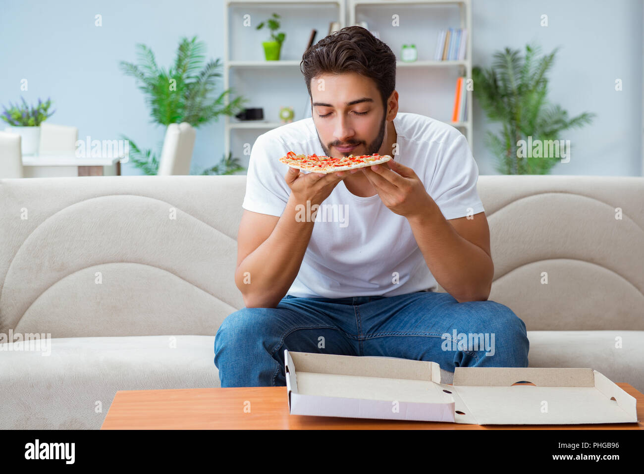 Man eating pizza having a takeaway at home relaxing resting Stock Photo ...