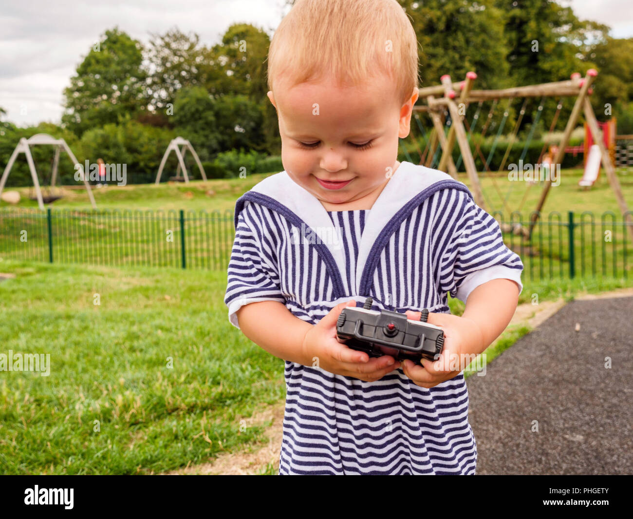 baby boy in blue sailor suit excited by holding toy remote controller ...