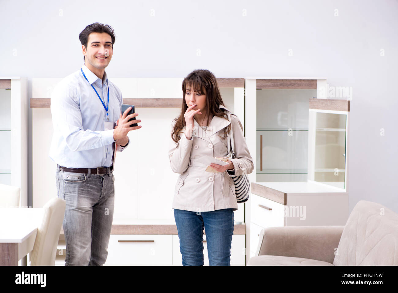 Salesman explaining to woman customer at furniture store Stock Photo ...