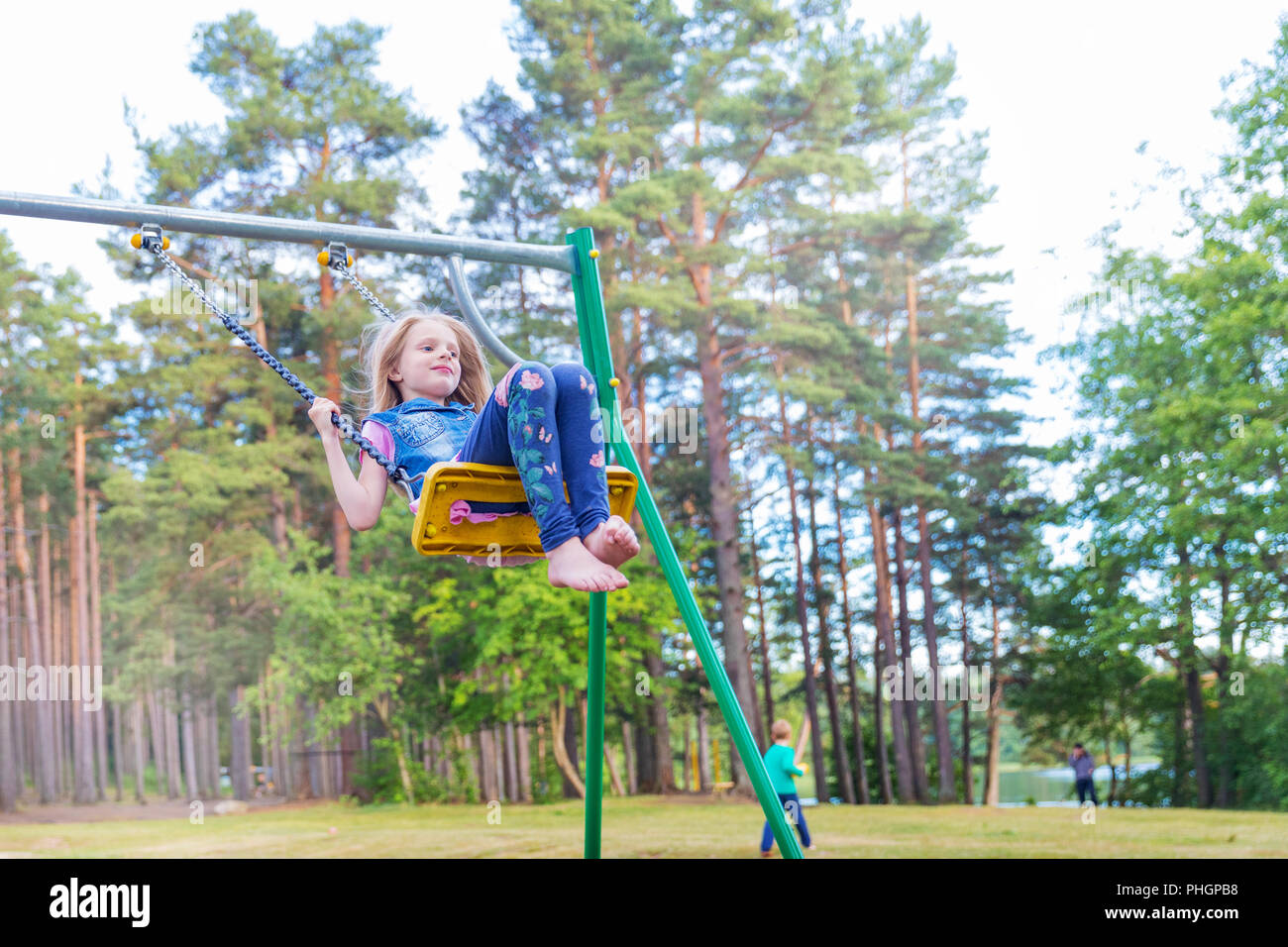 Pretty little blonde girl swinging outdoors on a playground Stock Photo ...