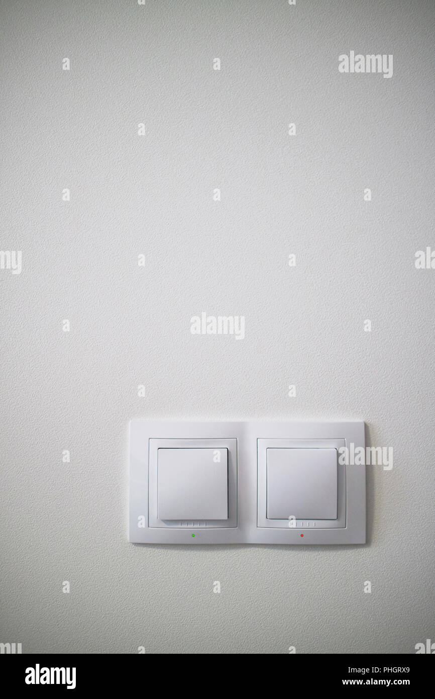 Electric two white lighting switchs on concrete wall Stock Photo - Alamy