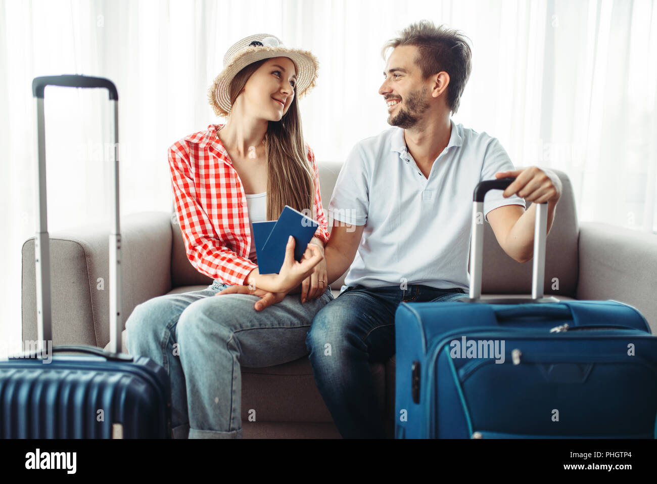 Young couple with suitcases sitting on the couch. Fees on journey ...