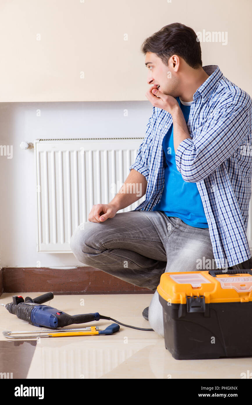 Young repairman contractor repairing heating panel Stock Photo - Alamy