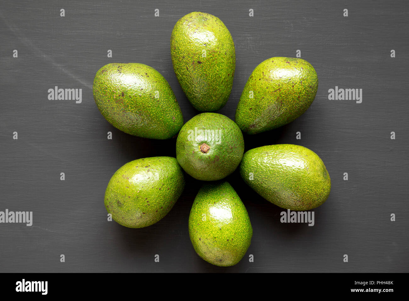 Whole avocados on dark background, overhead view. From above, flat lay ...
