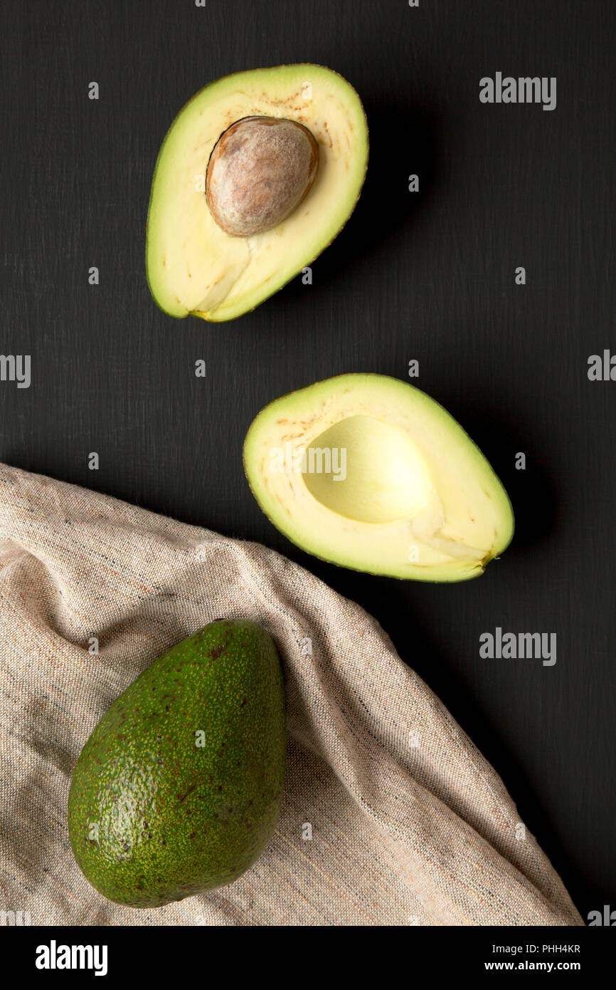 Whole and halved avocados on black table, top view Stock Photo - Alamy