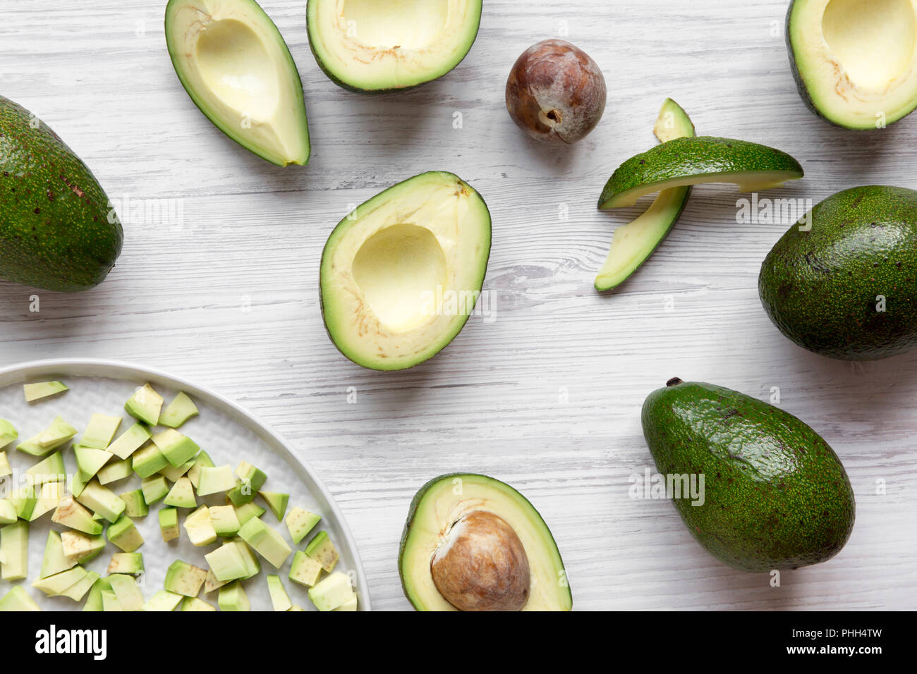 Whole and chopped avocados on white wooden background, view from above ...