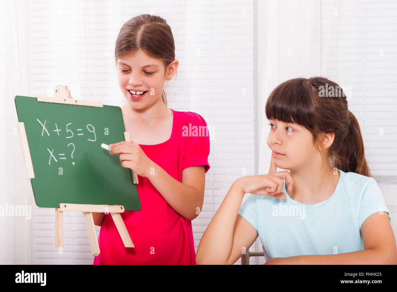 Cute little girls are helping each other with homework Stock Photo - Alamy