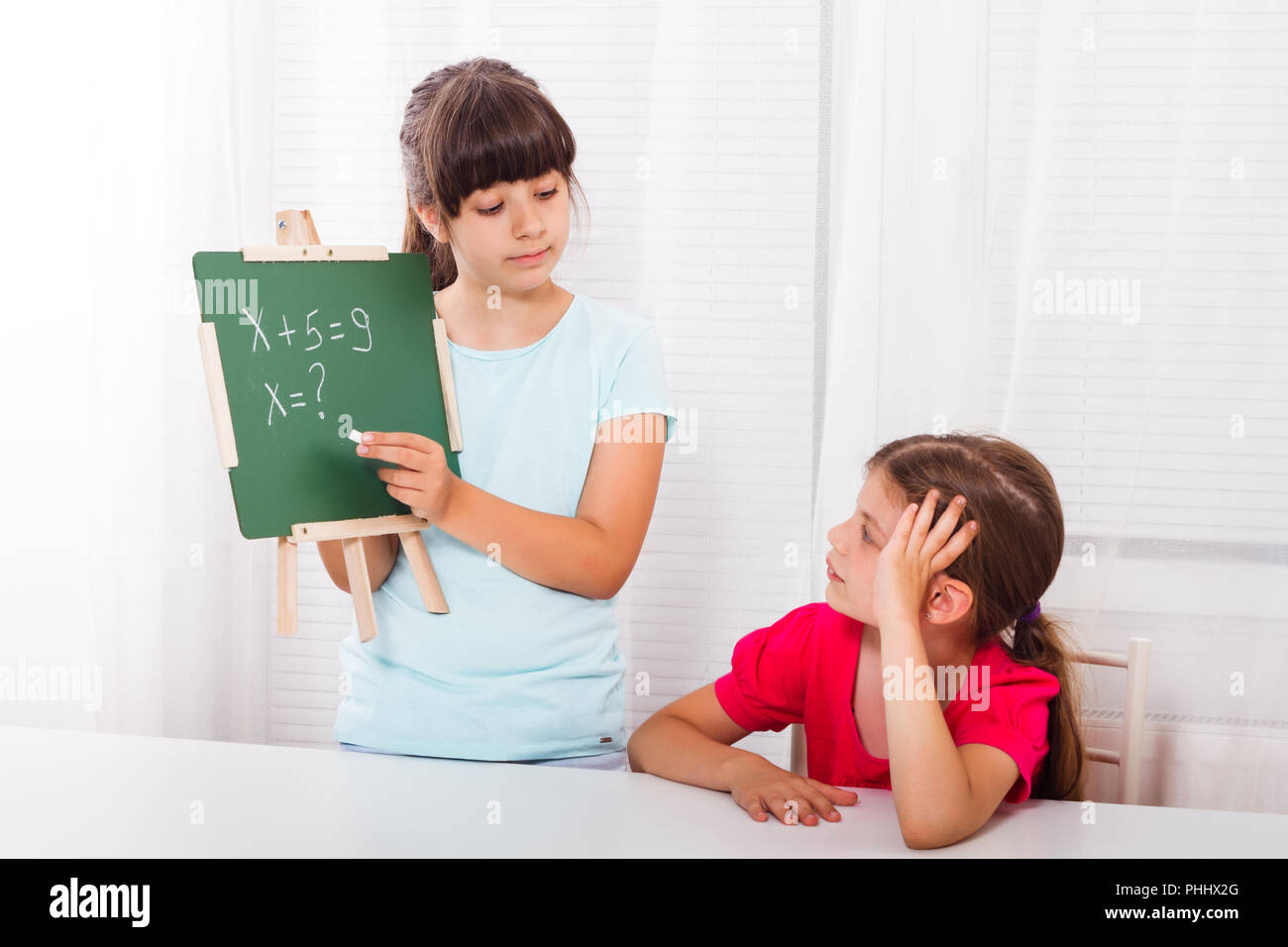 Cute little girls are helping each other with homework Stock Photo - Alamy