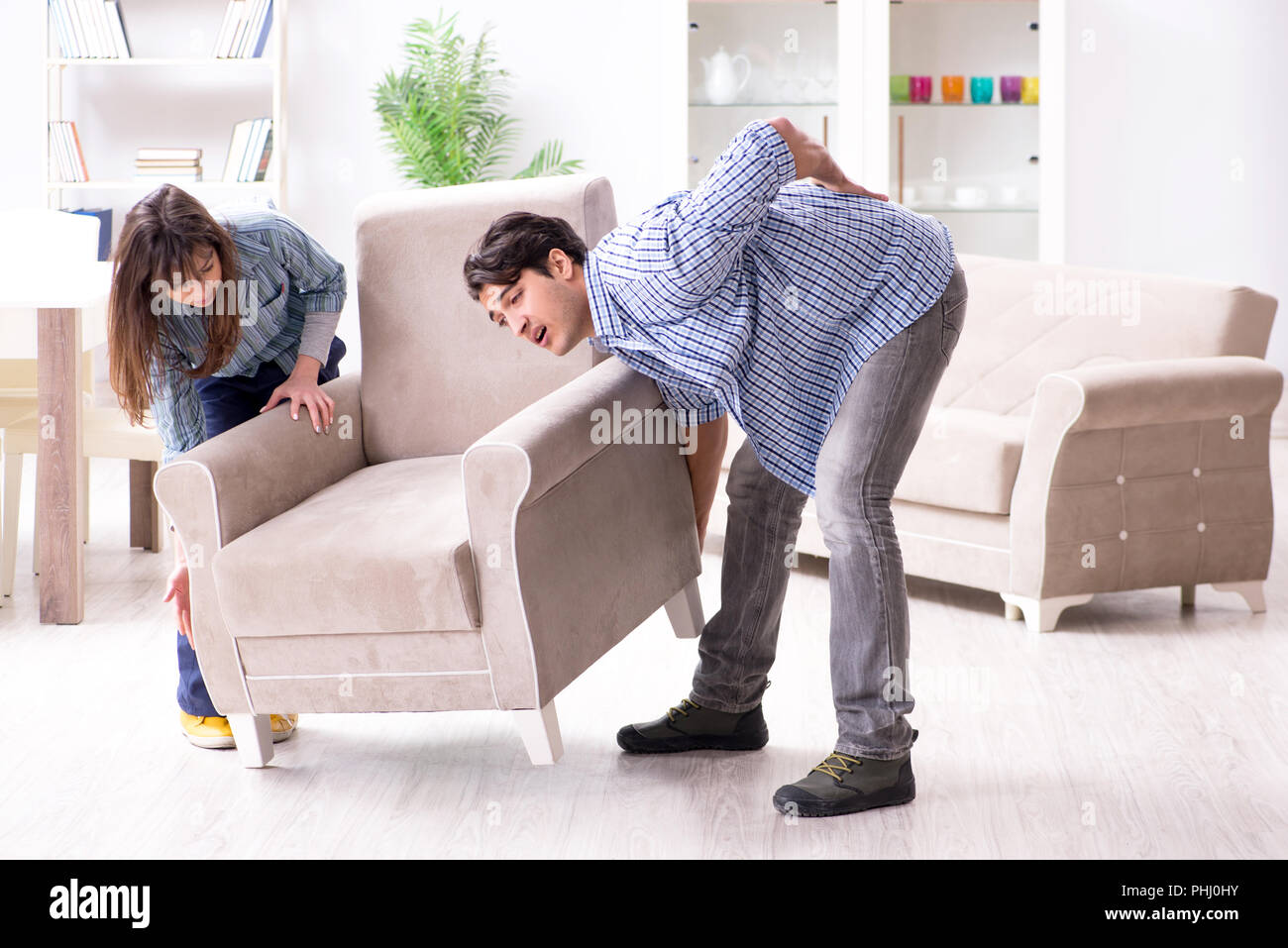 Man moving armchair in the living room Stock Photo - Alamy