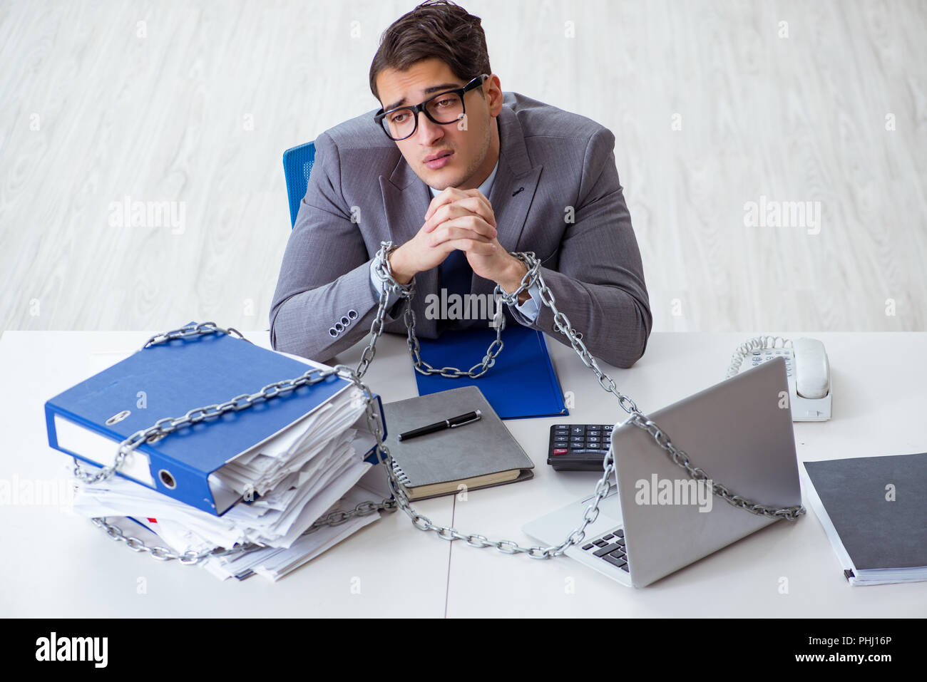 Busy employee chained to his office desk Stock Photo - Alamy