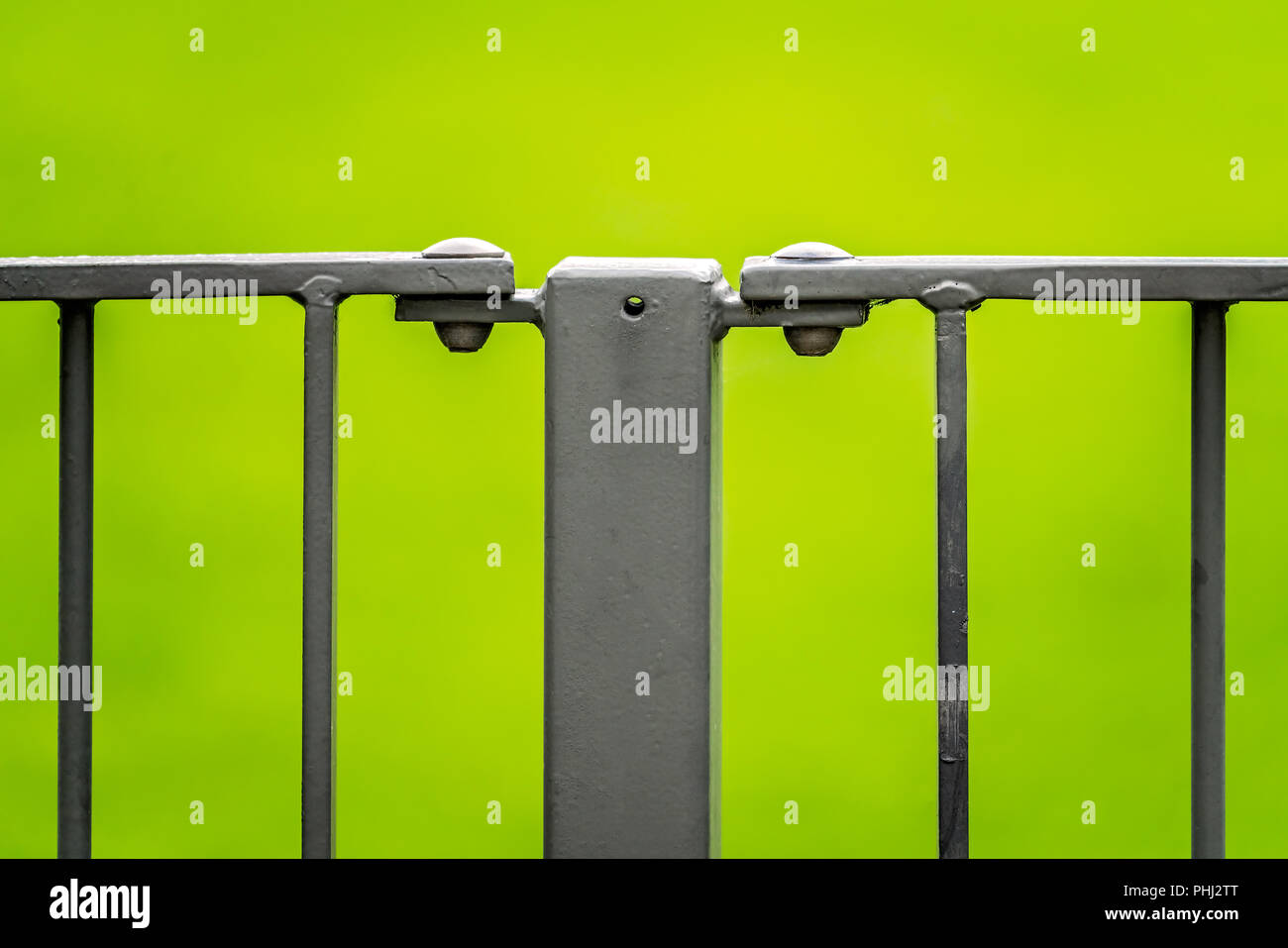 Metal gate fence detail over green background Stock Photo - Alamy