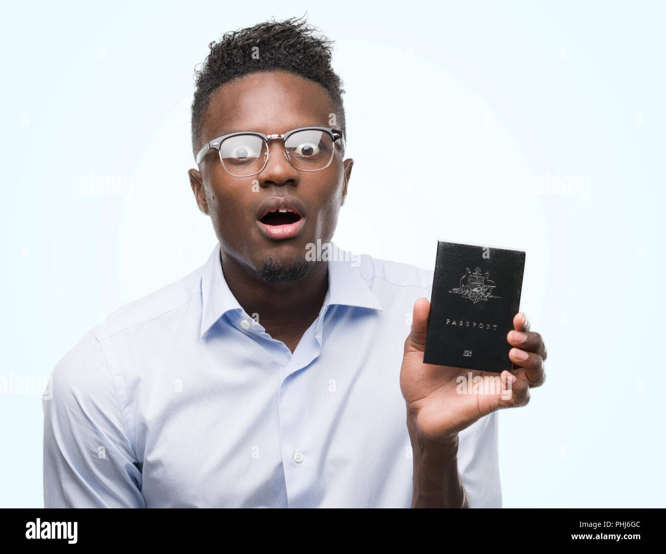 Young african american man holding australian passport scared in shock ...