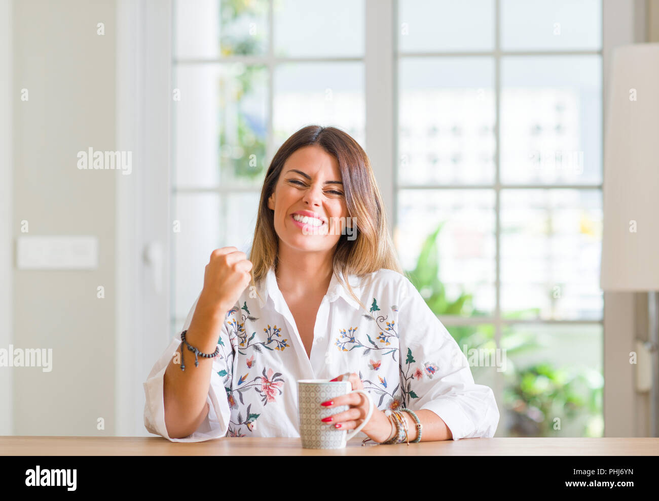 Young woman at home drinking coffee annoyed and frustrated shouting ...