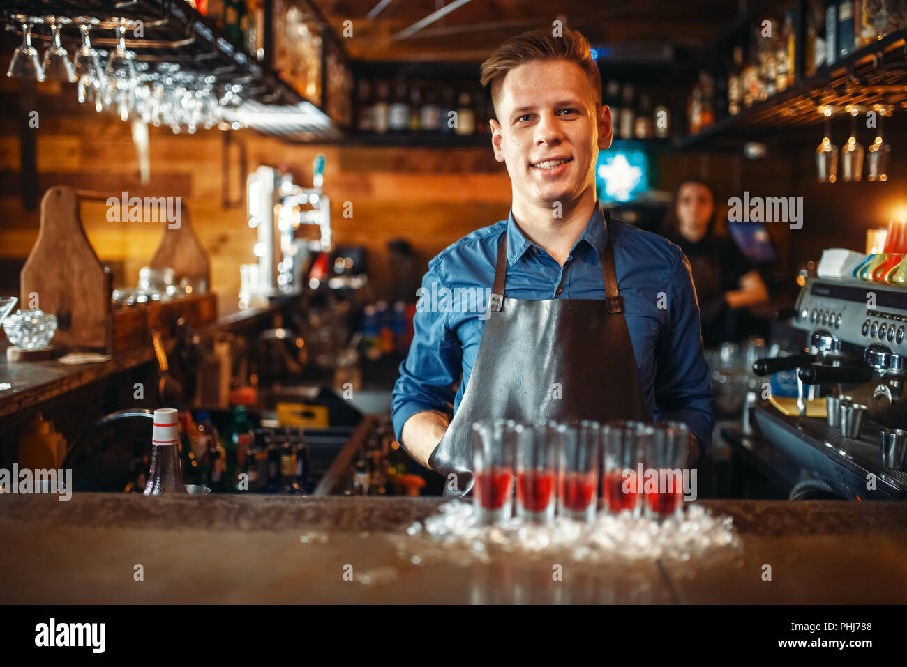 Male barman at the bar counter with glasses standing in ice. Bartender ...