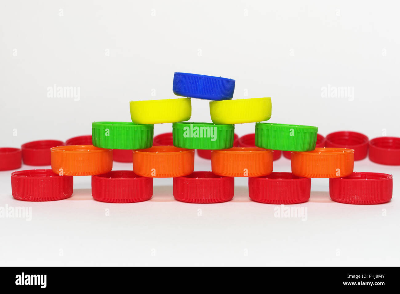 colorful plastic bottle caps, lined up in pyramid ahead of red row ...
