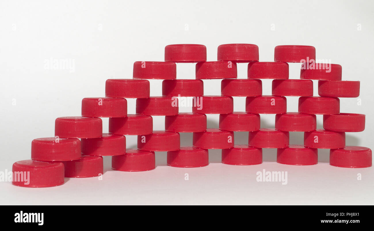 rows of red ribbed plastic bottle caps laying on each other. through ...