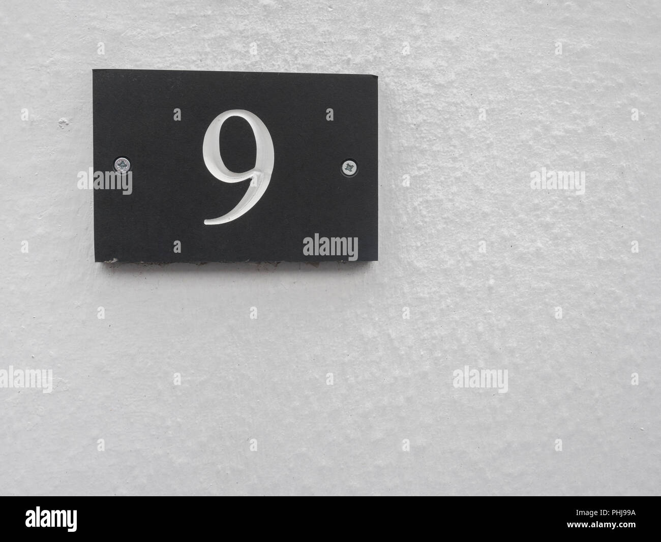House wall with a Number 9 plaque. Odd number Stock Photo - Alamy