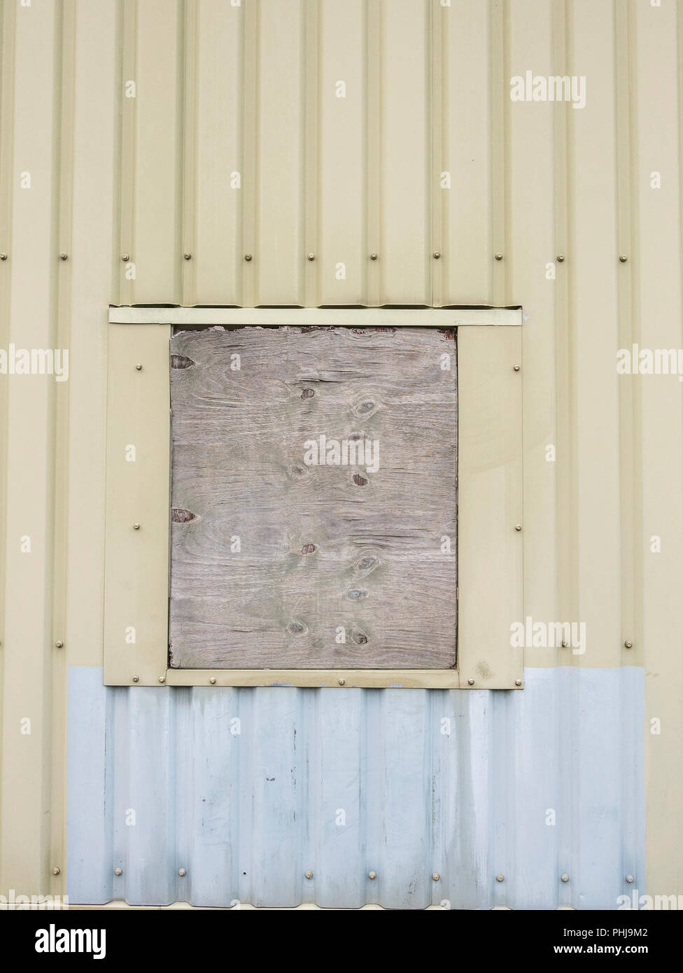 Broken window in side of industrial shed blocked by plywood panel Stock ...