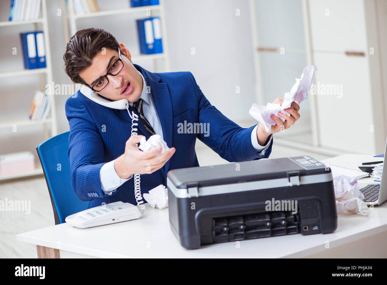 Businessman angry at copying machine jamming papers Stock Photo - Alamy