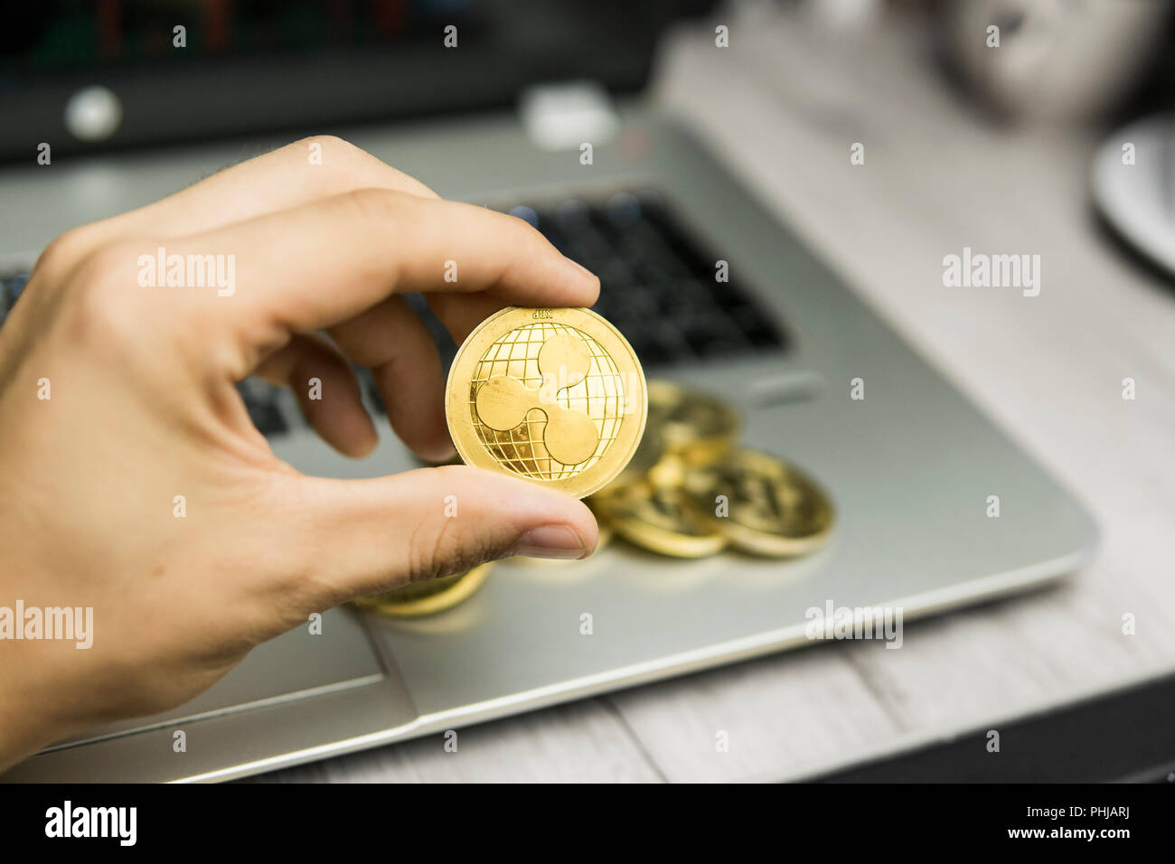 Male businessman hand holding Ripple coin on a background of laptop ...