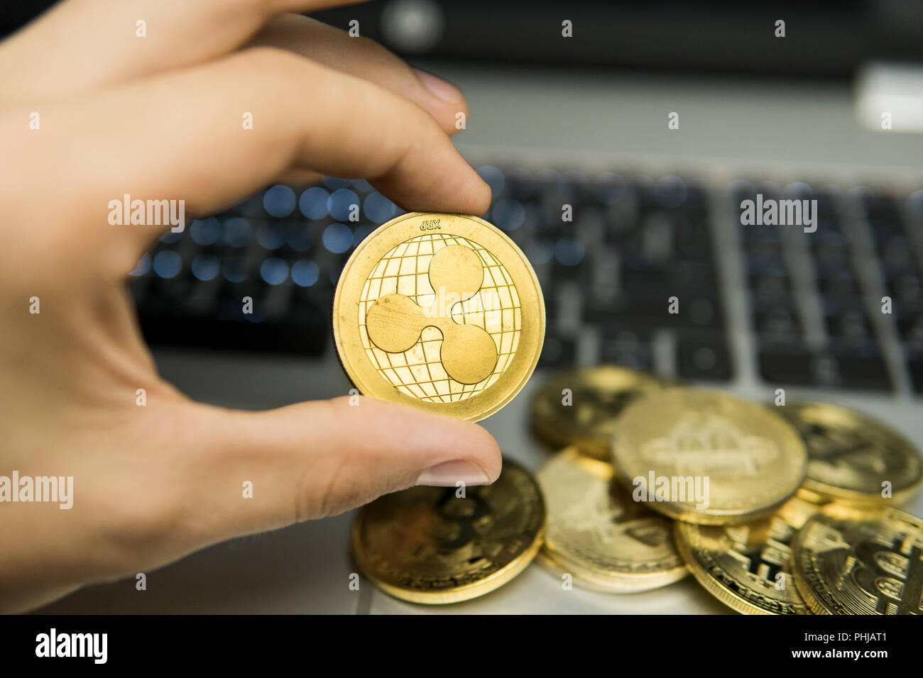 Male businessman hand holding Ripple coin on a background of laptop ...