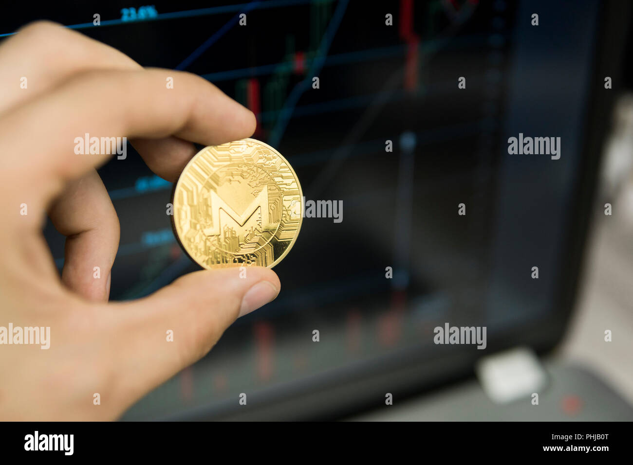 Male businessman hand holding Monero coin on a background of growth ...