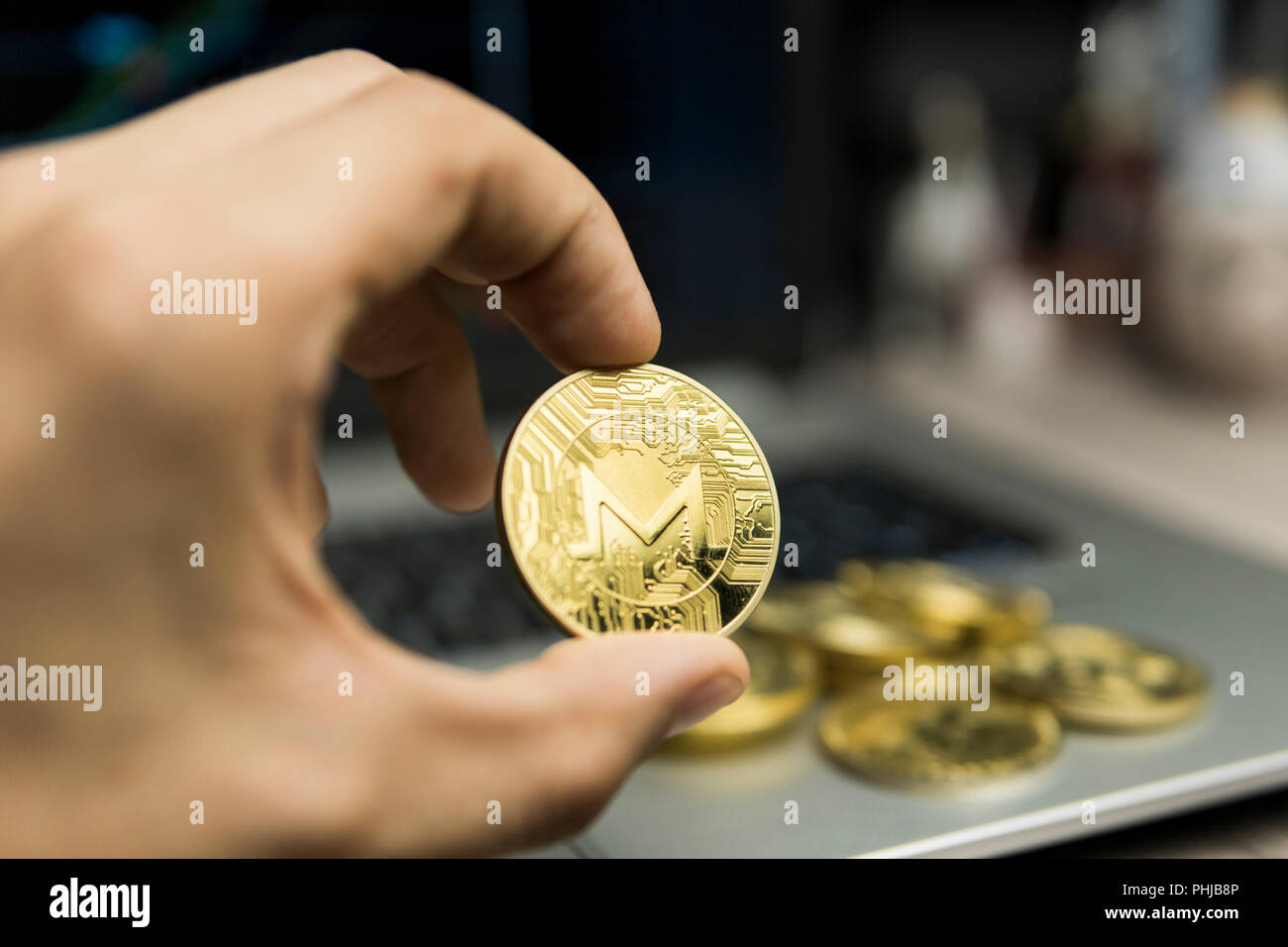 Male businessman hand holding Monero coin on a background of laptop ...