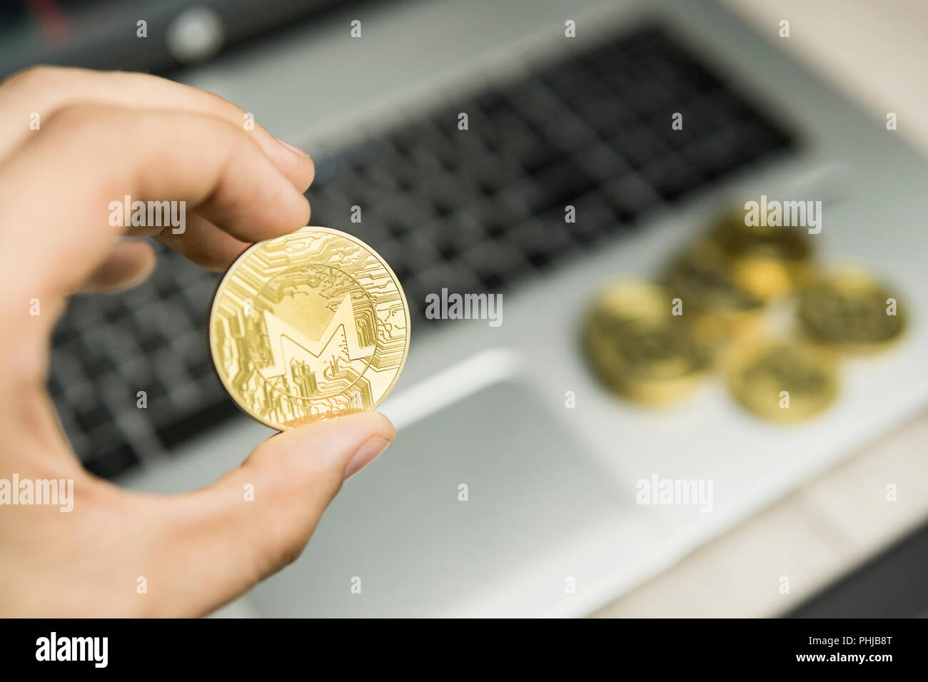 Male businessman hand holding Monero coin on a background of laptop ...