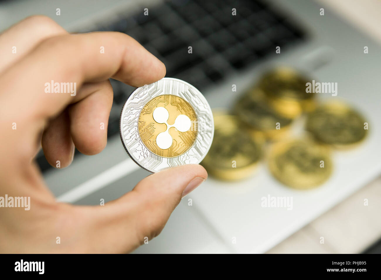 Male businessman hand holding Ripple coin on a background of laptop ...