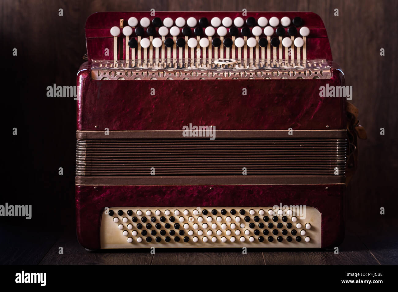 Old red accordion on brown wooden background Stock Photo - Alamy