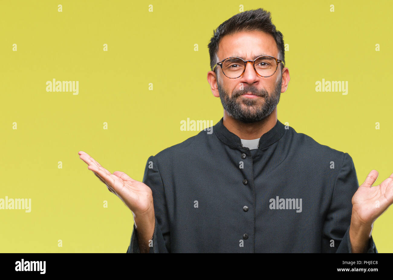 Adult hispanic catholic priest man over isolated background clueless ...