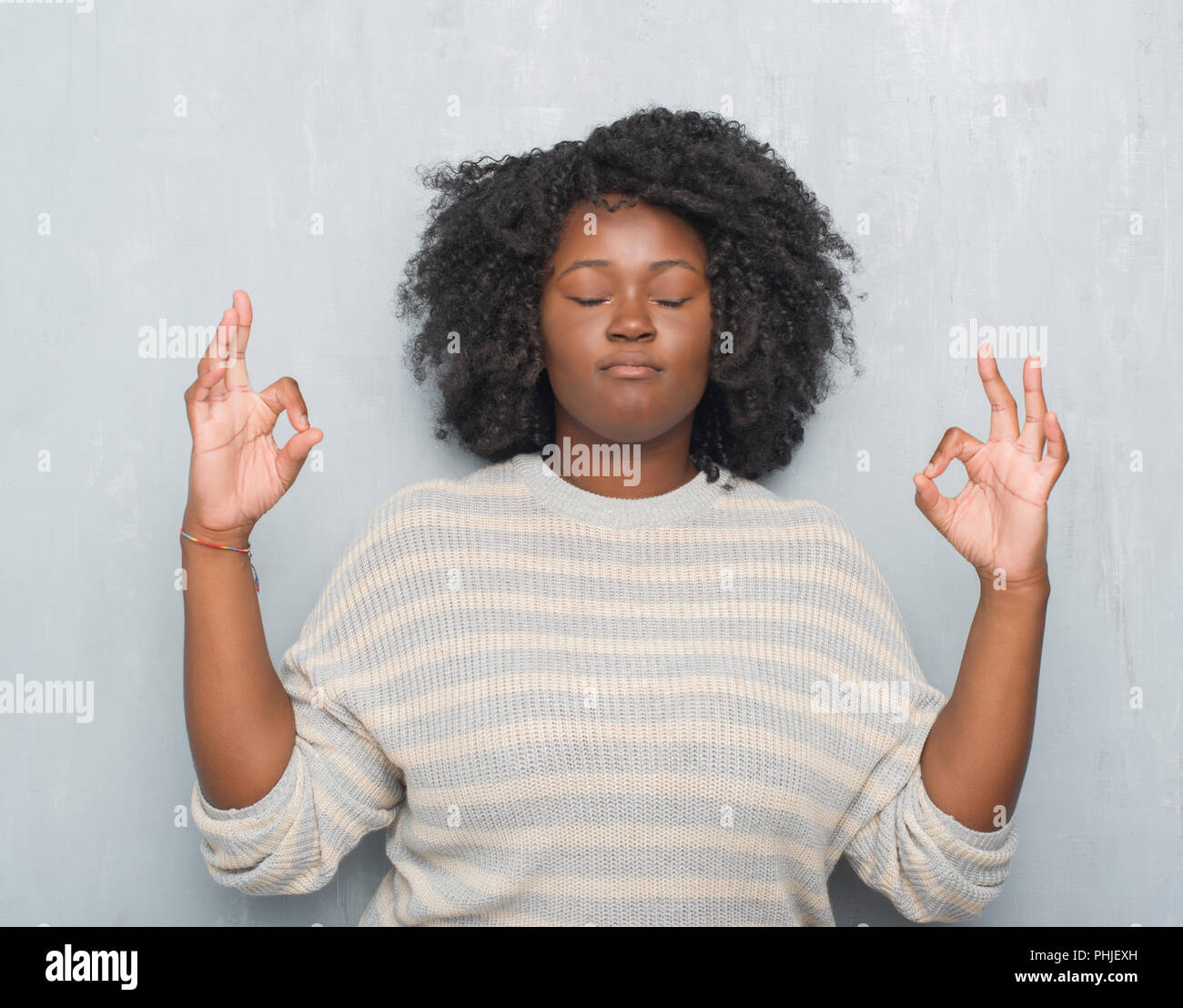Young african american plus size woman over grey grunge wall wearing a ...