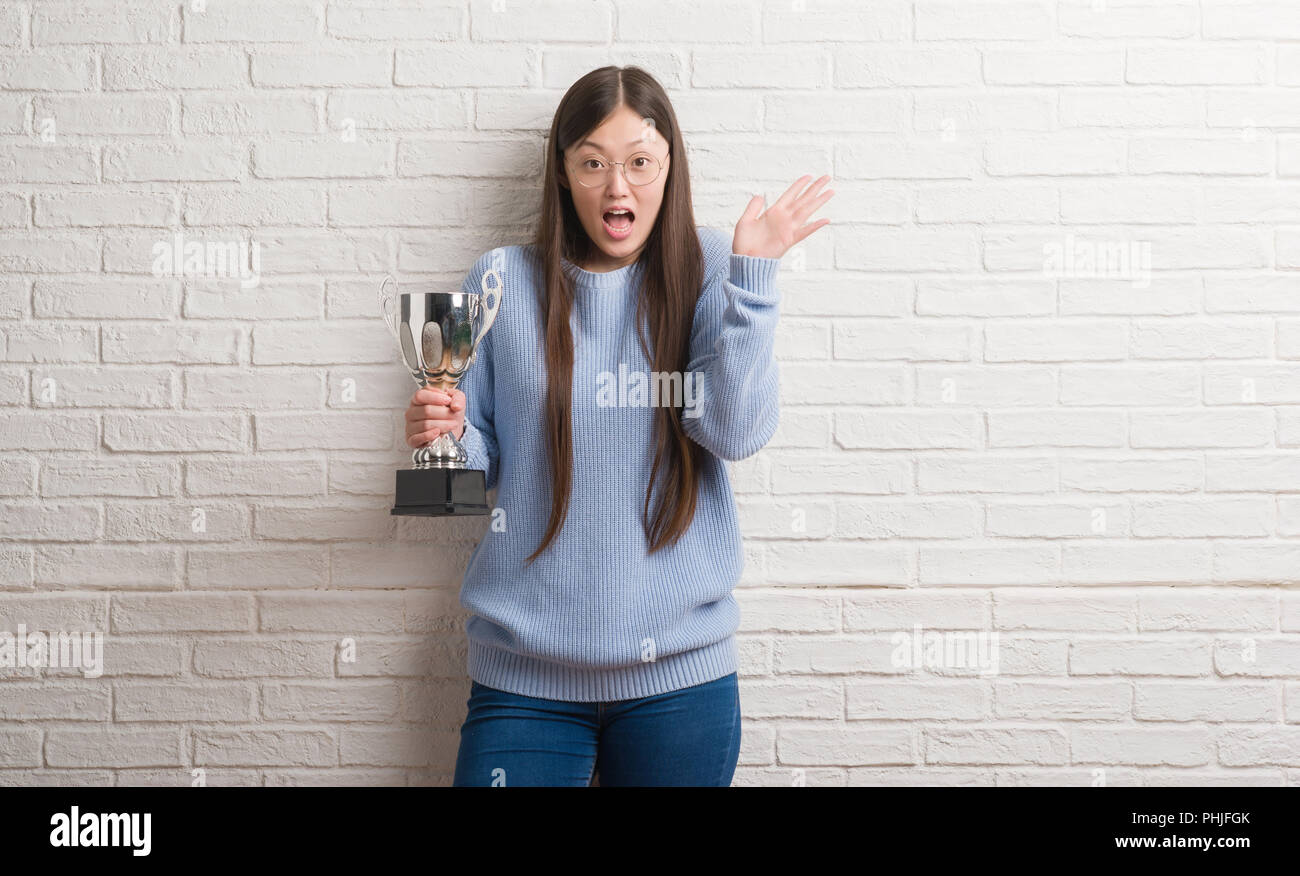 Young Chinese woman holding trophy very happy and excited, winner ...