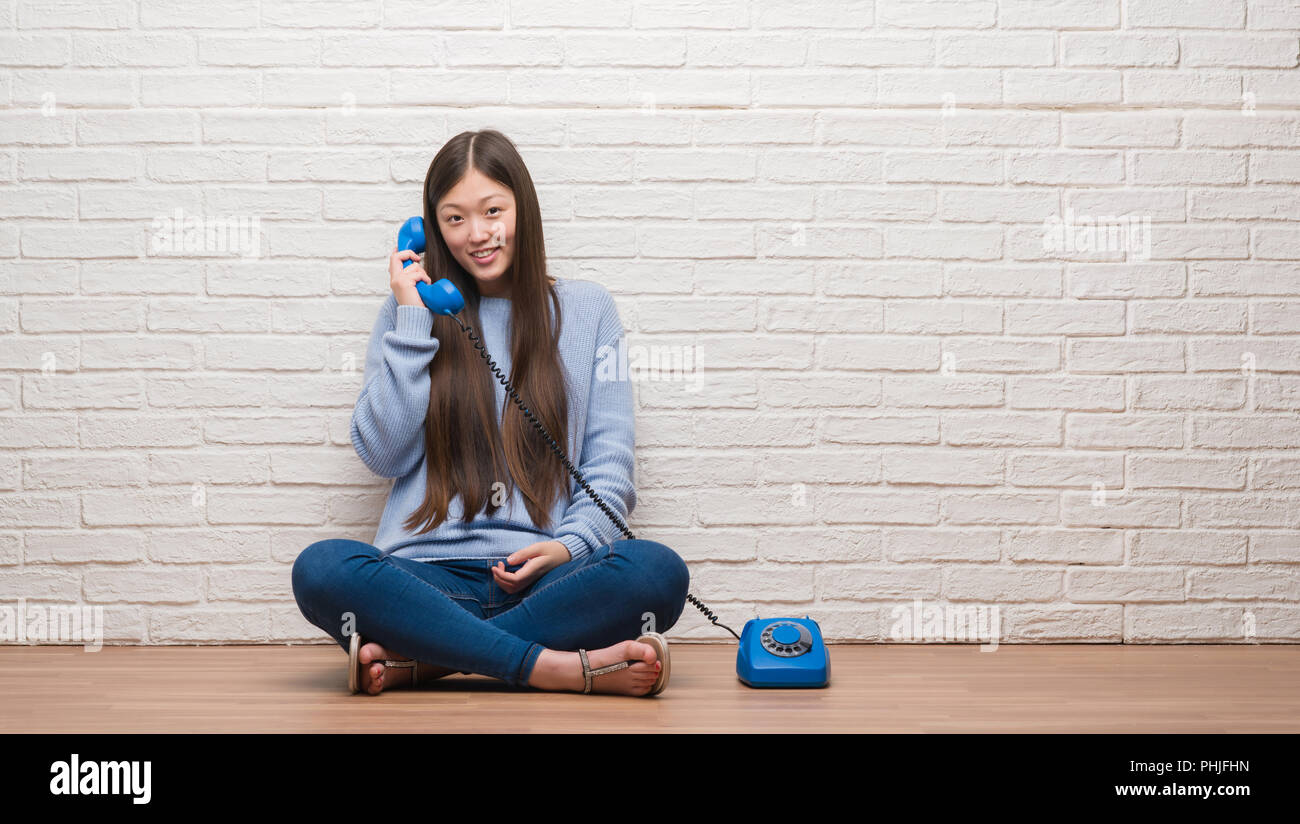 Young Chinese woman calling using vintage telephone with a happy face ...
