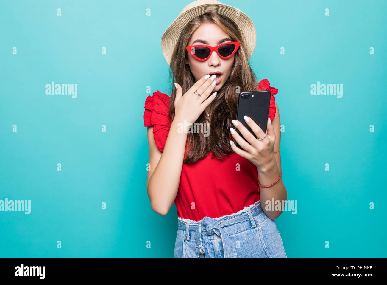 Portrait if a shocked young girl in dress looking at mobile phone ...