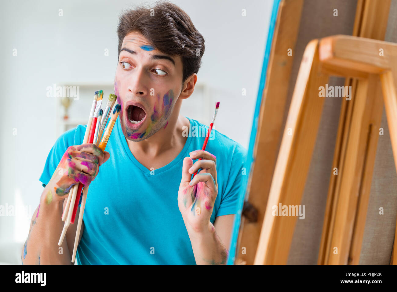 Young funny artist working on new painting in his studio Stock Photo ...