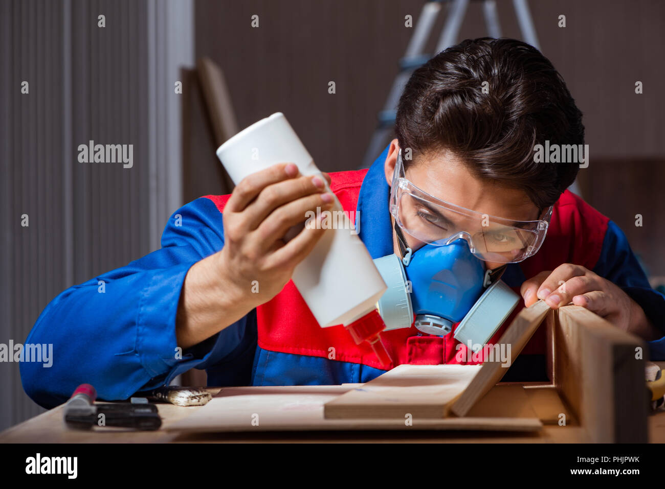 Young man gluing wood pieces together in DIY concept Stock Photo - Alamy