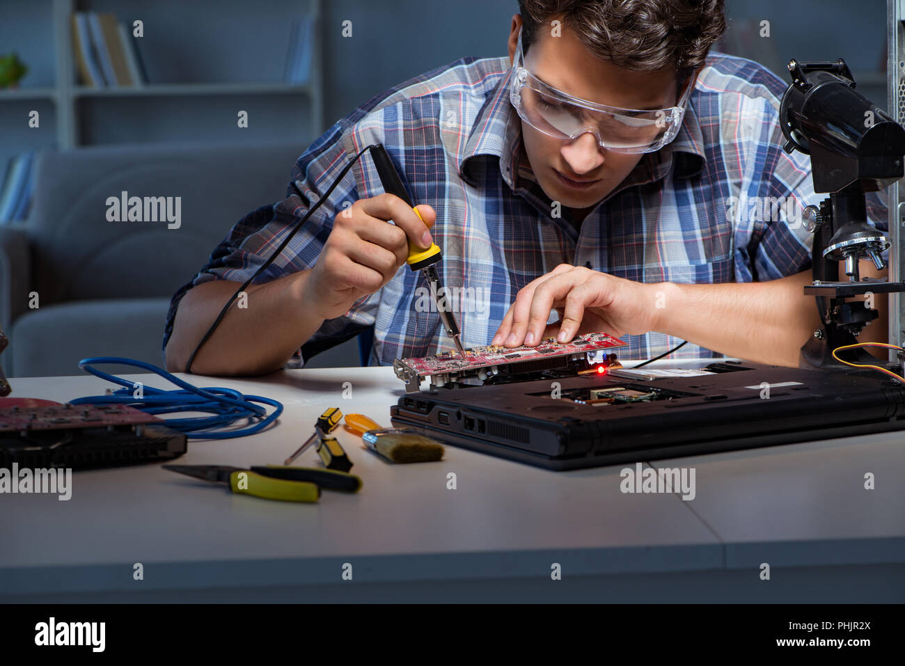 Young repair technician soldering electrical parts on motherboar Stock ...