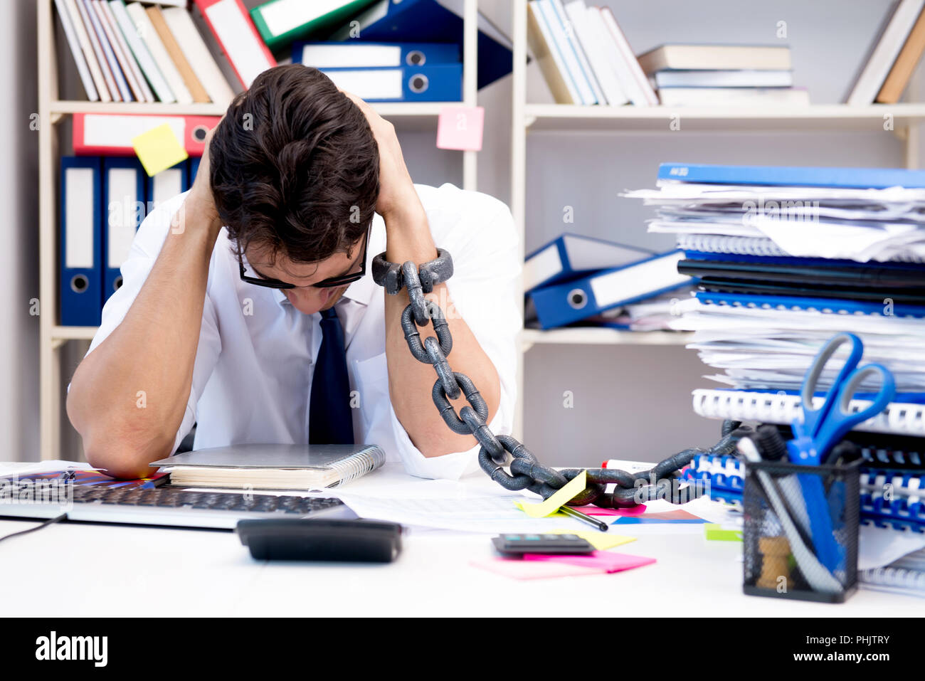 Employee attached and chained to his desk with chain Stock Photo - Alamy