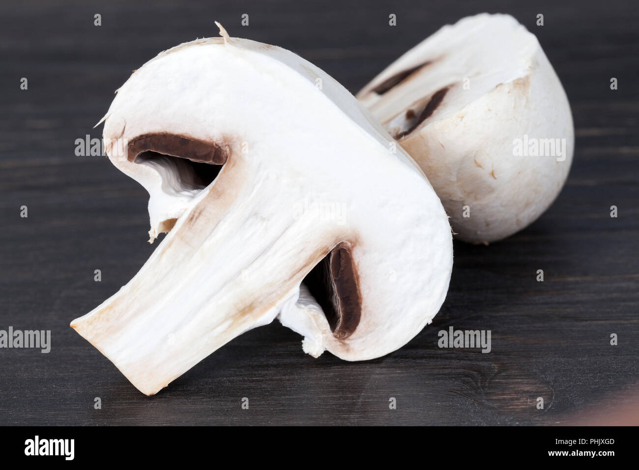 cut into half and pieces of white champignon on a black background ...
